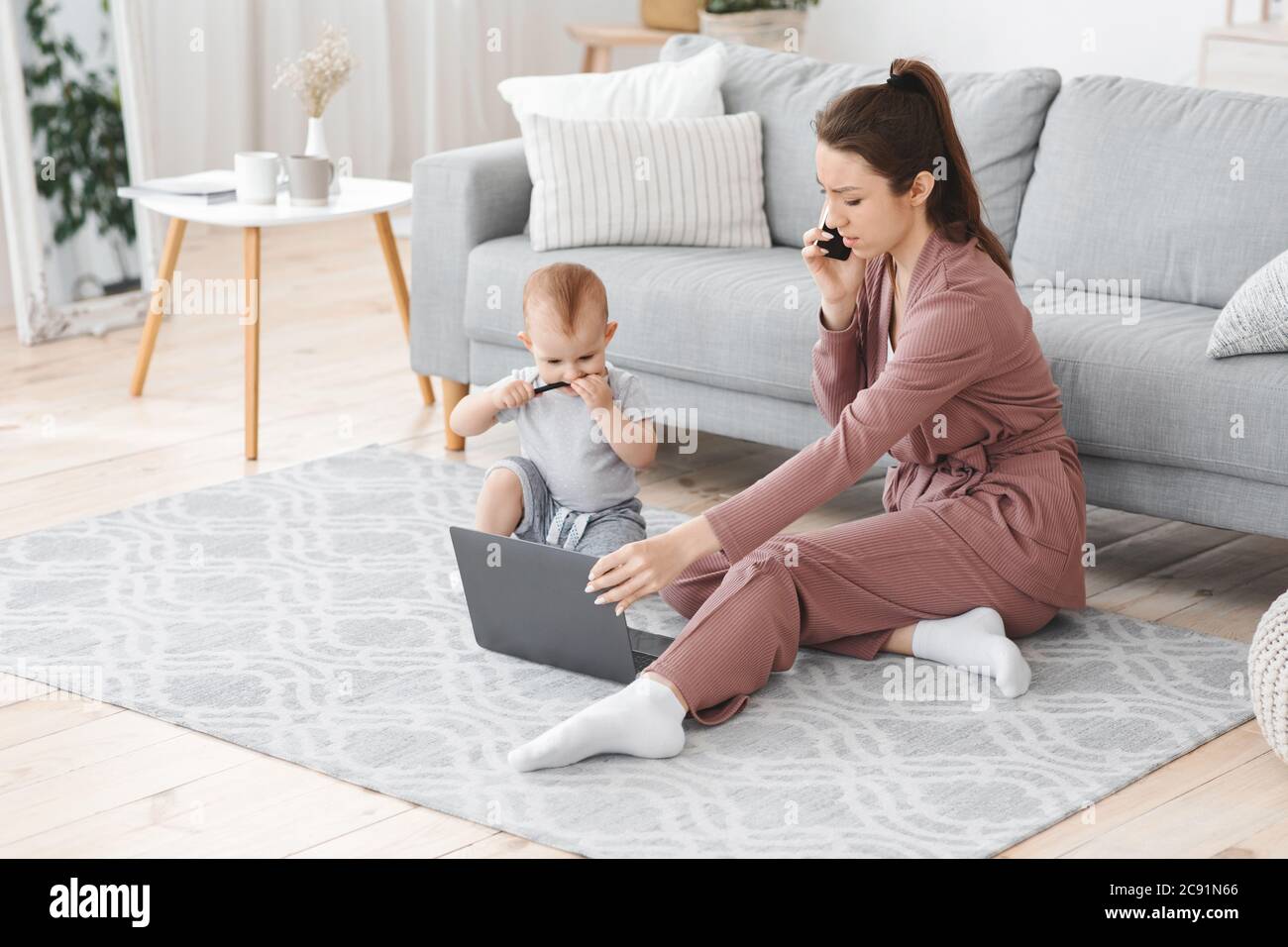 Motherhood And Multitasking. Mom Working At Home While Baby Distructing ...