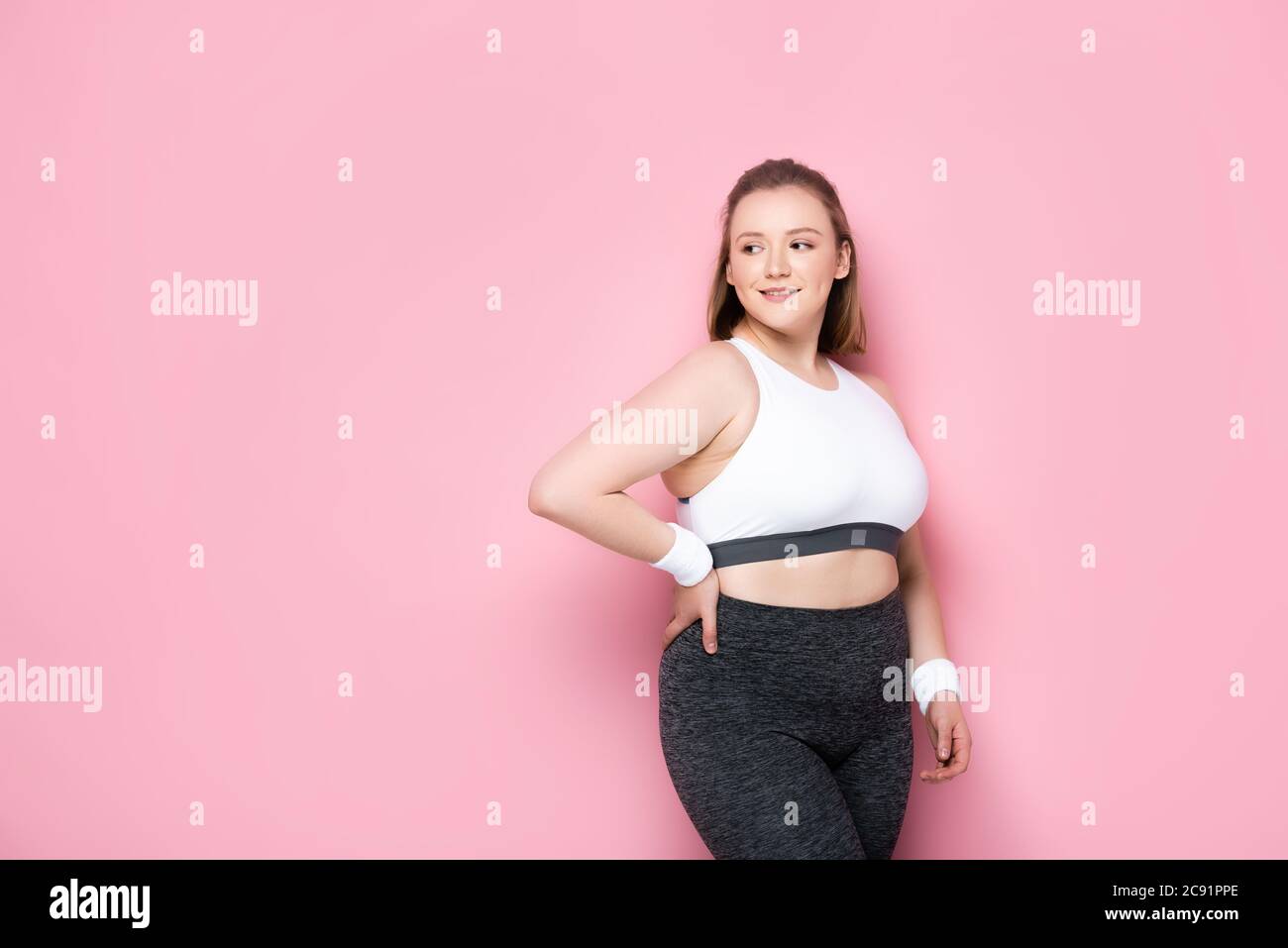 pretty, smiling overweight girl standing with hand on hip on pink Stock ...