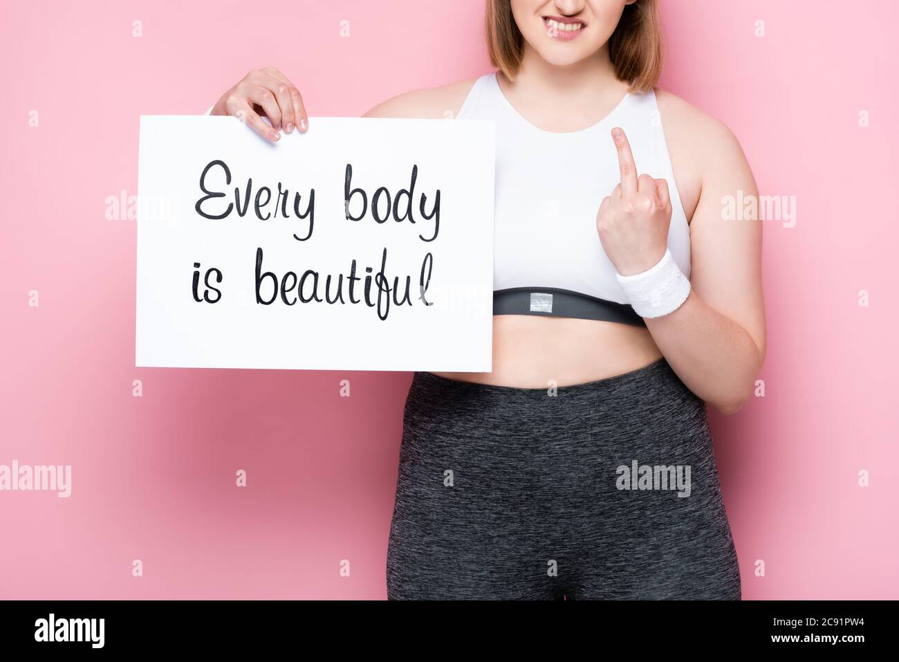 cropped view of overweight girl showing middle finger while holding ...
