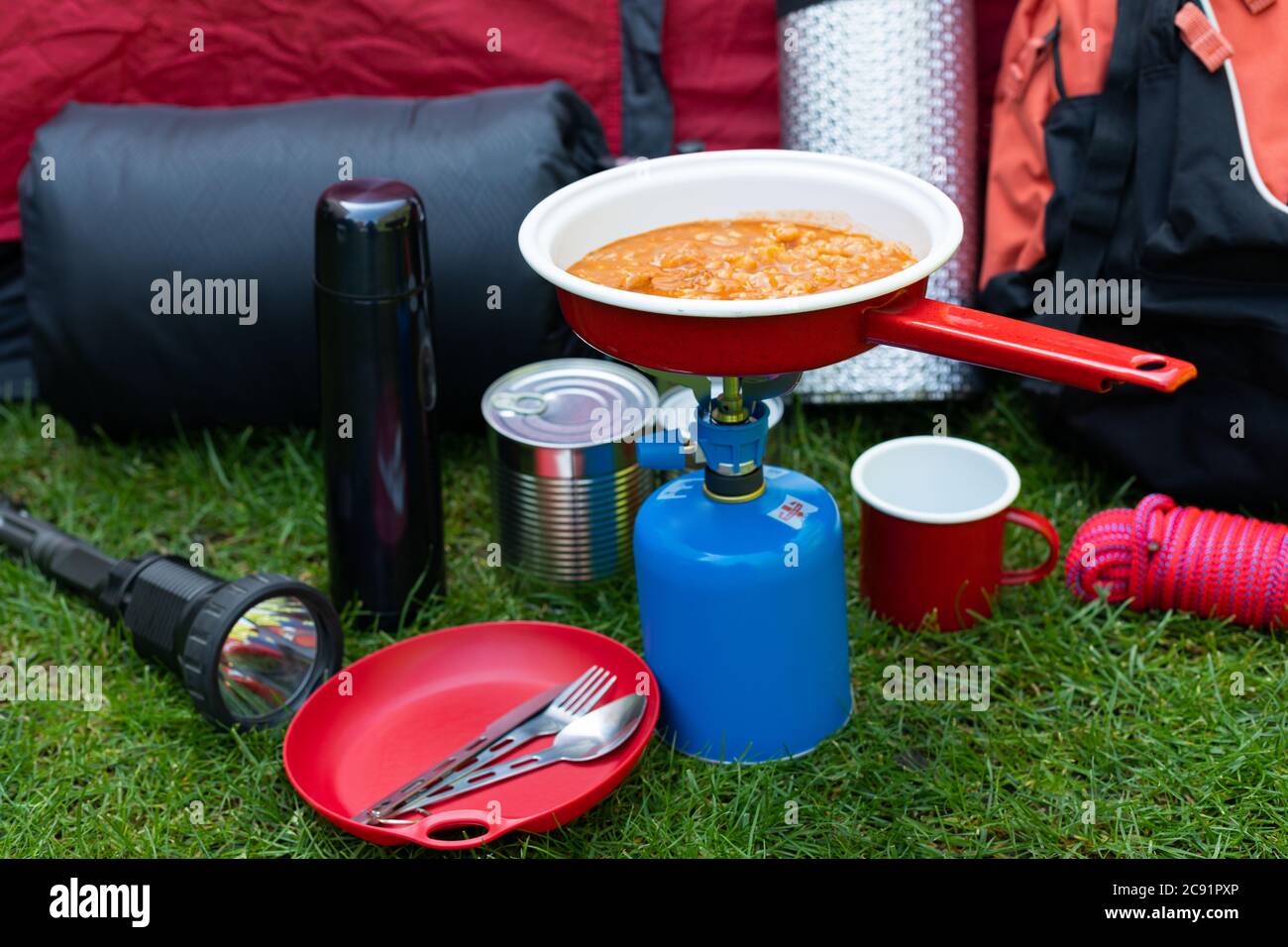 Picture of camping tools on the grass - backpack, tent, gas tank, cans ...