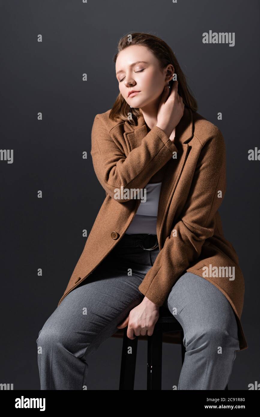 beautiful plus size girl sitting on chair and touching neck while ...