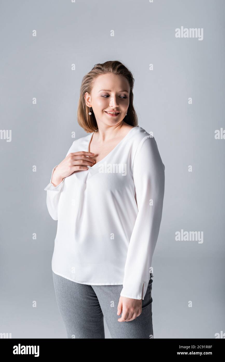 smiling, elegant overweight girl holding hand on chest while posing ...