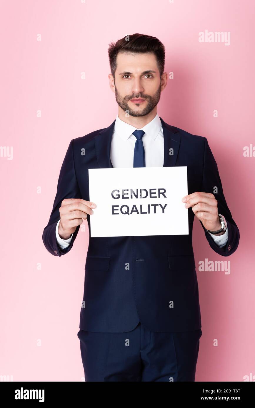 businessman holding placard with gender equality lettering on pink ...
