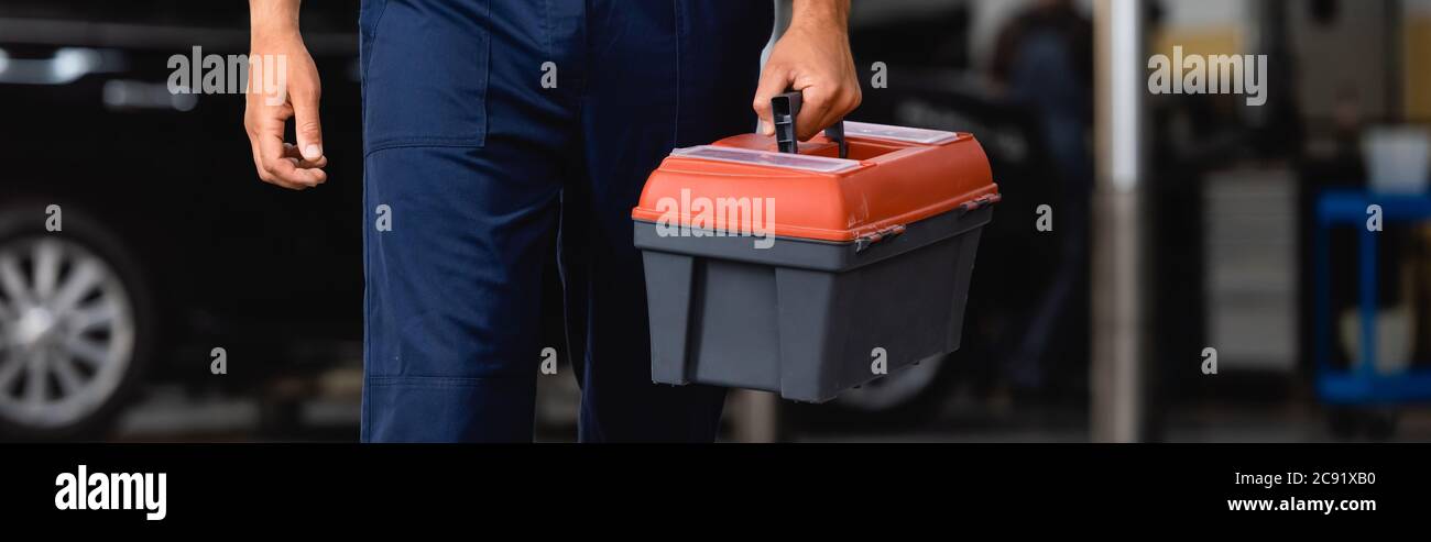 horizontal image of mechanic in uniform holding toolbox in service ...