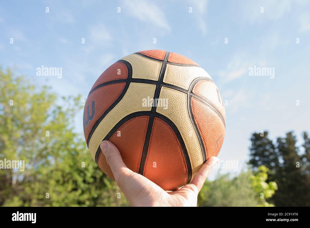 Man holding a basketball ball in one hand Stock Photo - Alamy