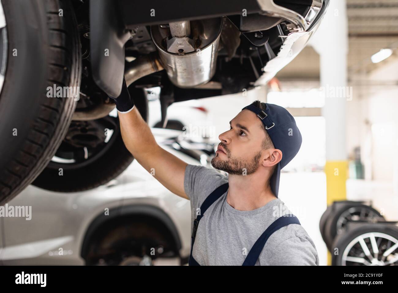selective focus of handsome mechanic in cap fixing car Stock Photo - Alamy