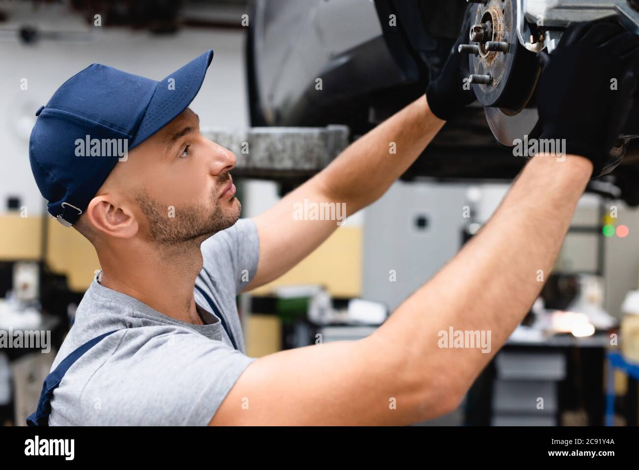 profile of mechanic in cap repairing car in service station Stock Photo ...