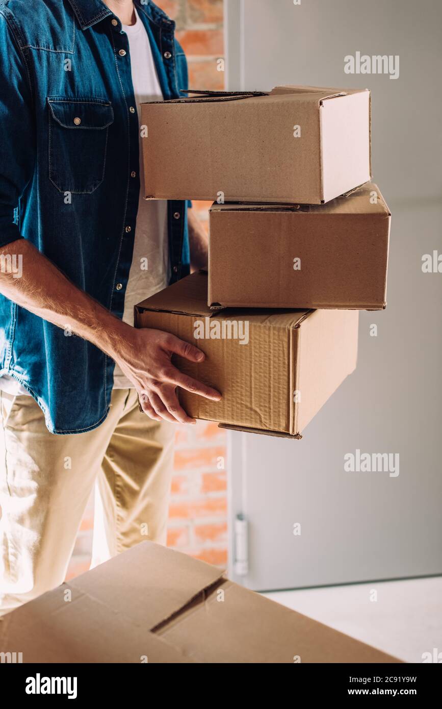 partial view of man holding carton boxes while moving in new office ...