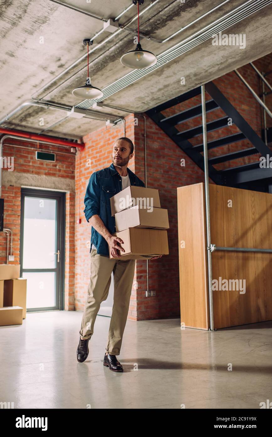handsome businessman holding boxes and walking in new and modern office ...