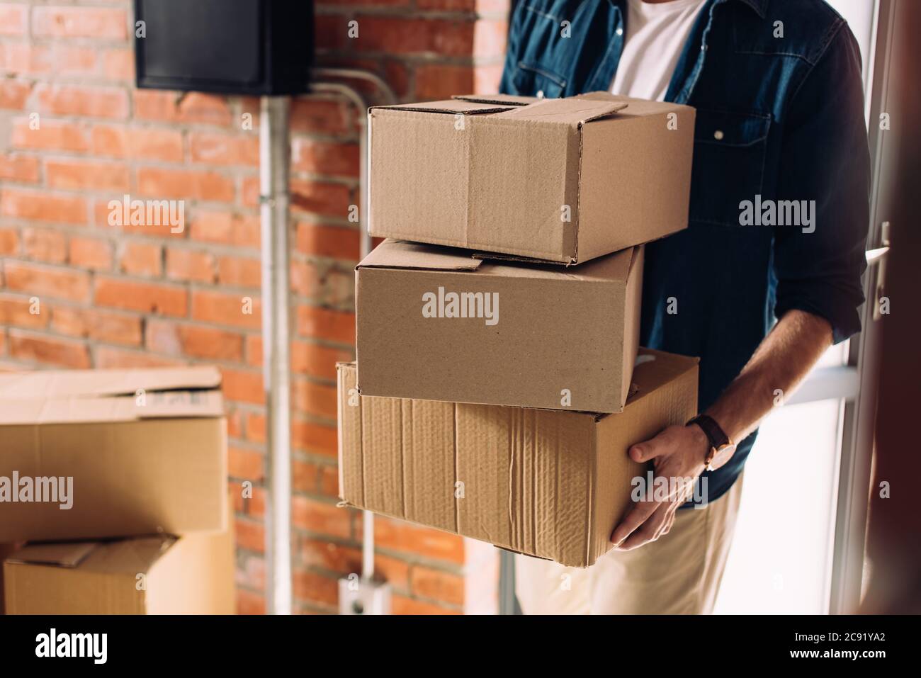 partial view of businessman holding carton boxes while walking in new ...