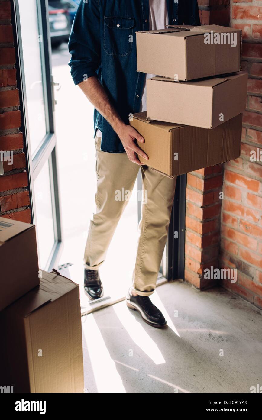 cropped view of businessman holding carton boxes while walking in new ...