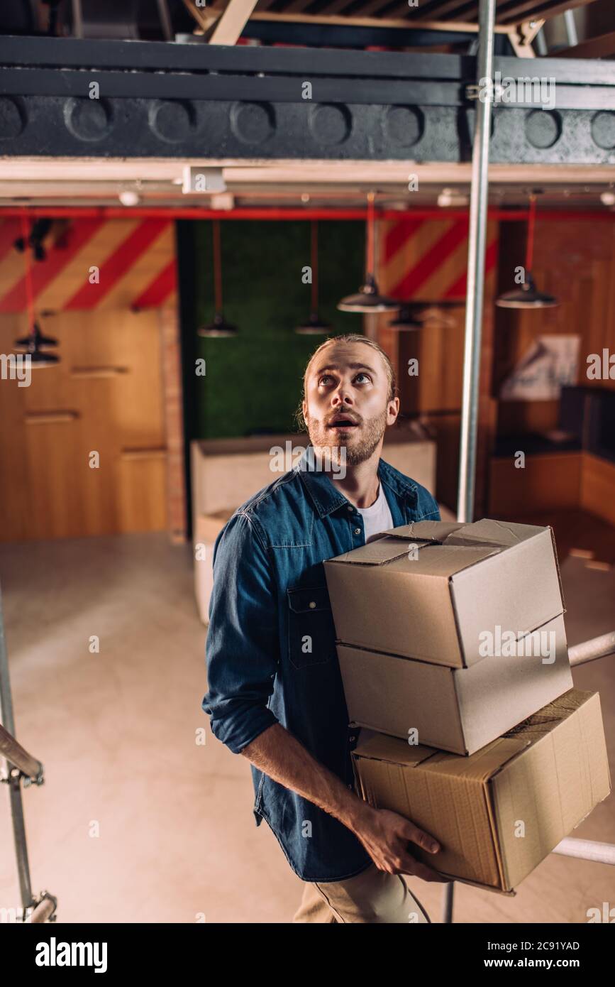 handsome businessman holding boxes and looking up in new office Stock ...