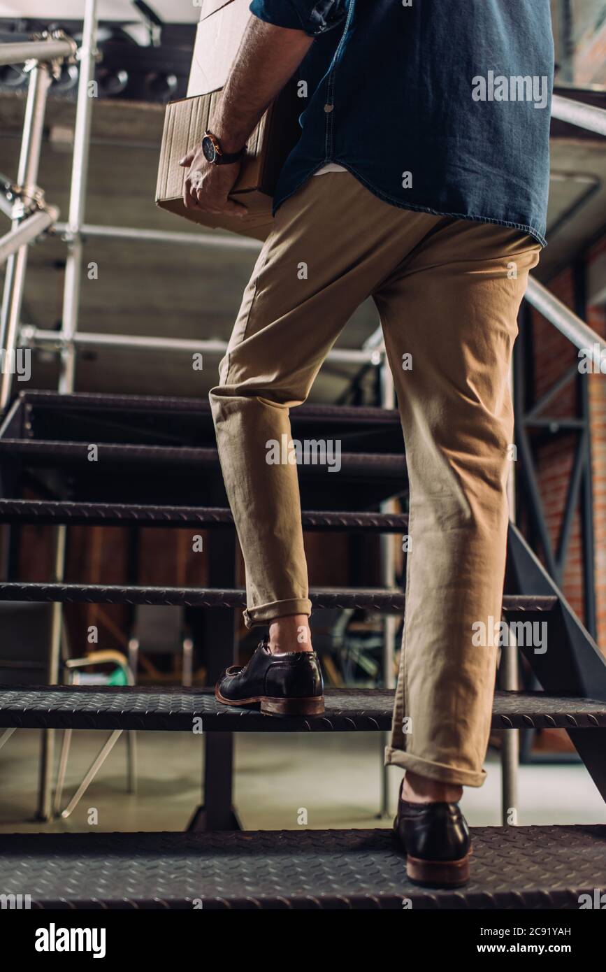 cropped view of businessman holding boxes while walking on stairs in ...