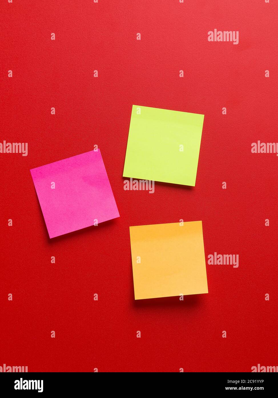 Top view of three colored reminder stickers in a red background, with ...