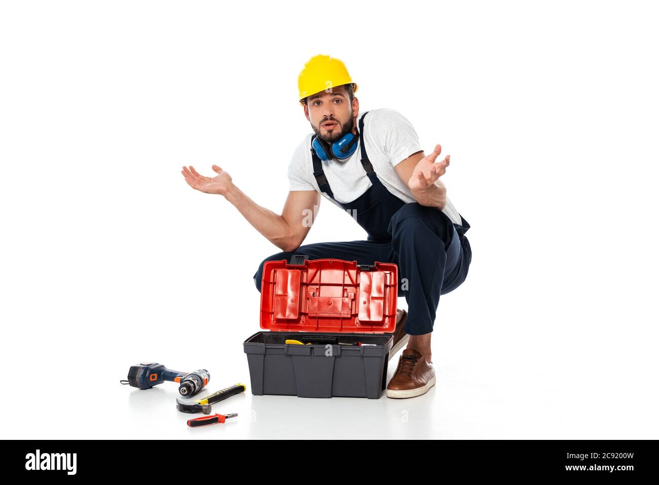Confused workman showing shrug gesture near tools and toolbox on on ...