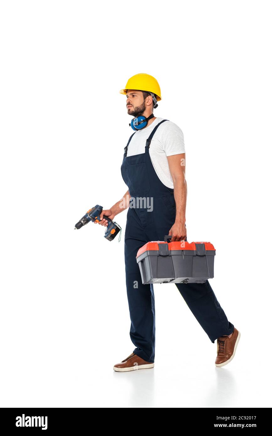 Handsome workman in overalls and hardhat holding toolbox and electric ...