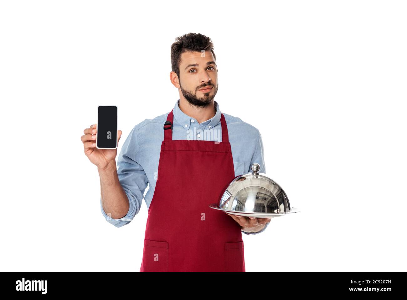 Handsome waiter holding smartphone and tray with cloche isolated on ...