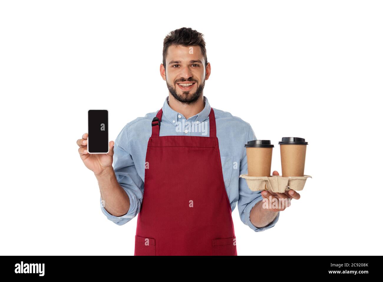 Handsome waiter smiling at camera while holding paper cups and ...