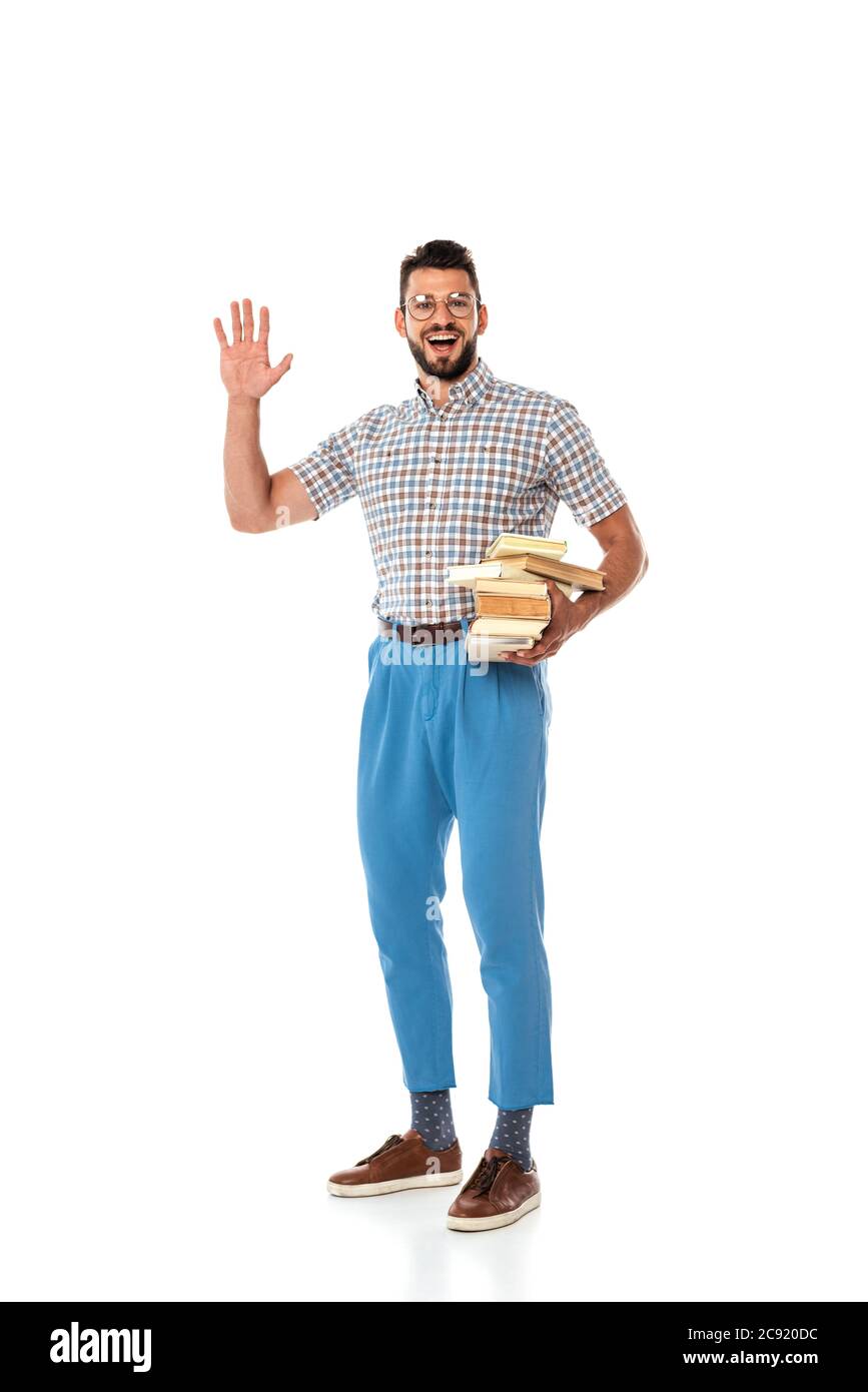 Smiling nerd holding books and waving hand at camera on white ...