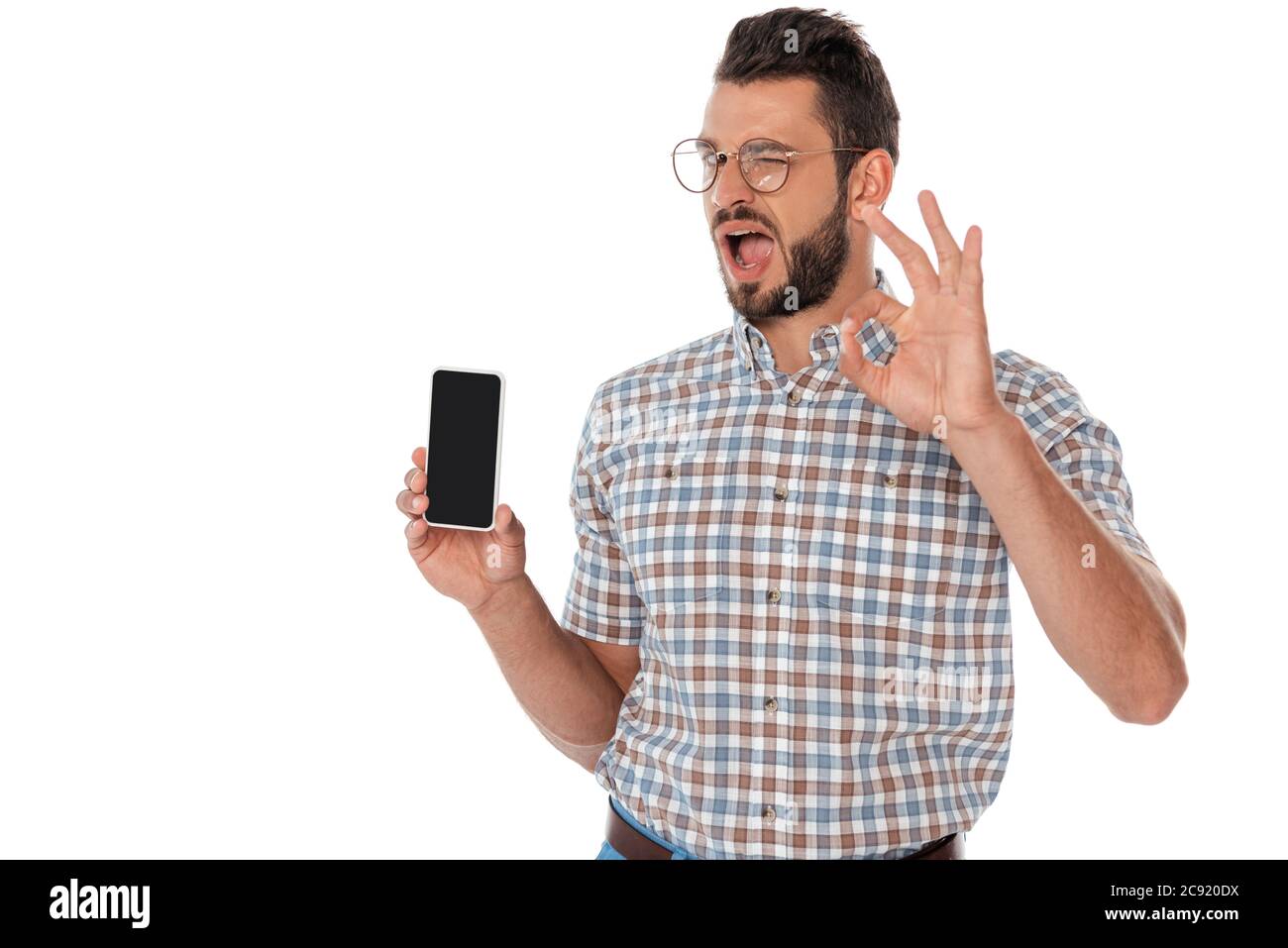 Nerd winking and showing ok gesture while holding smartphone isolated ...