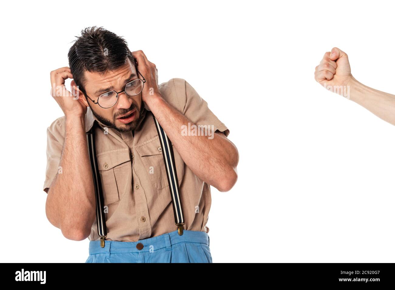 Scared nerd in eyeglasses covering ears near male fist isolated on ...