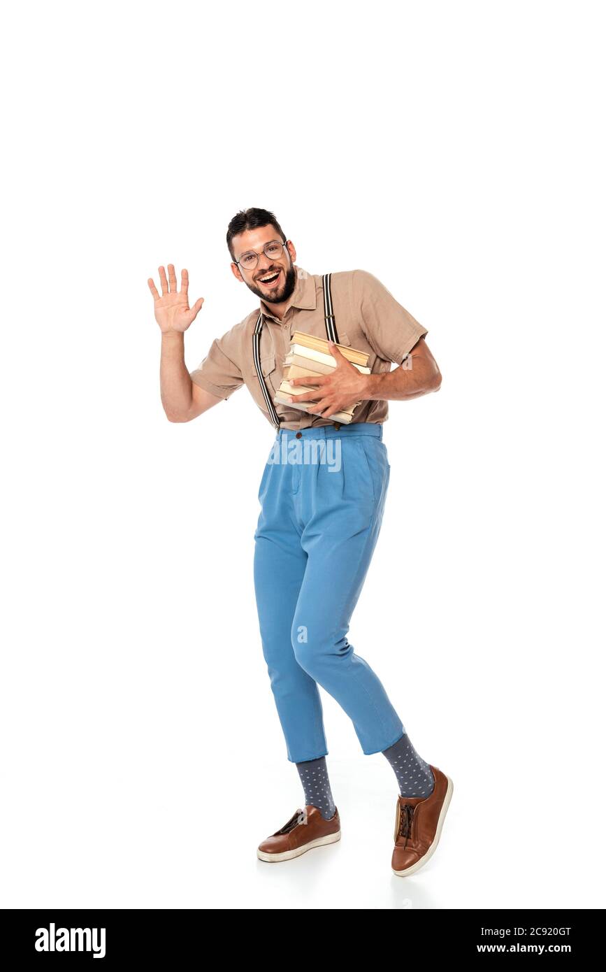 Cheerful nerd in suspenders holding books and waving hand at camera on ...
