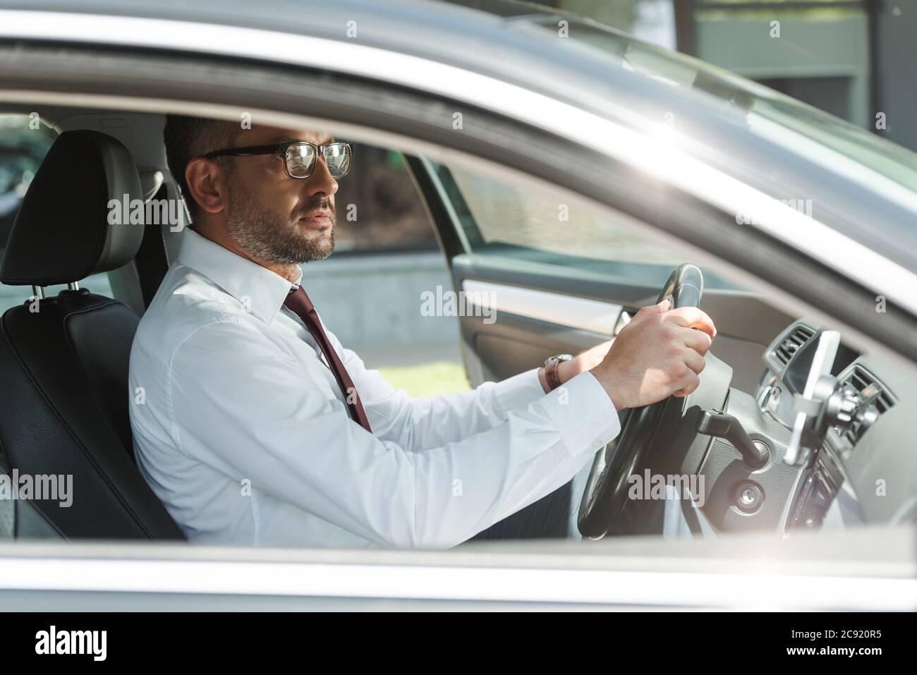 Side view of handsome businessman driving car Stock Photo - Alamy