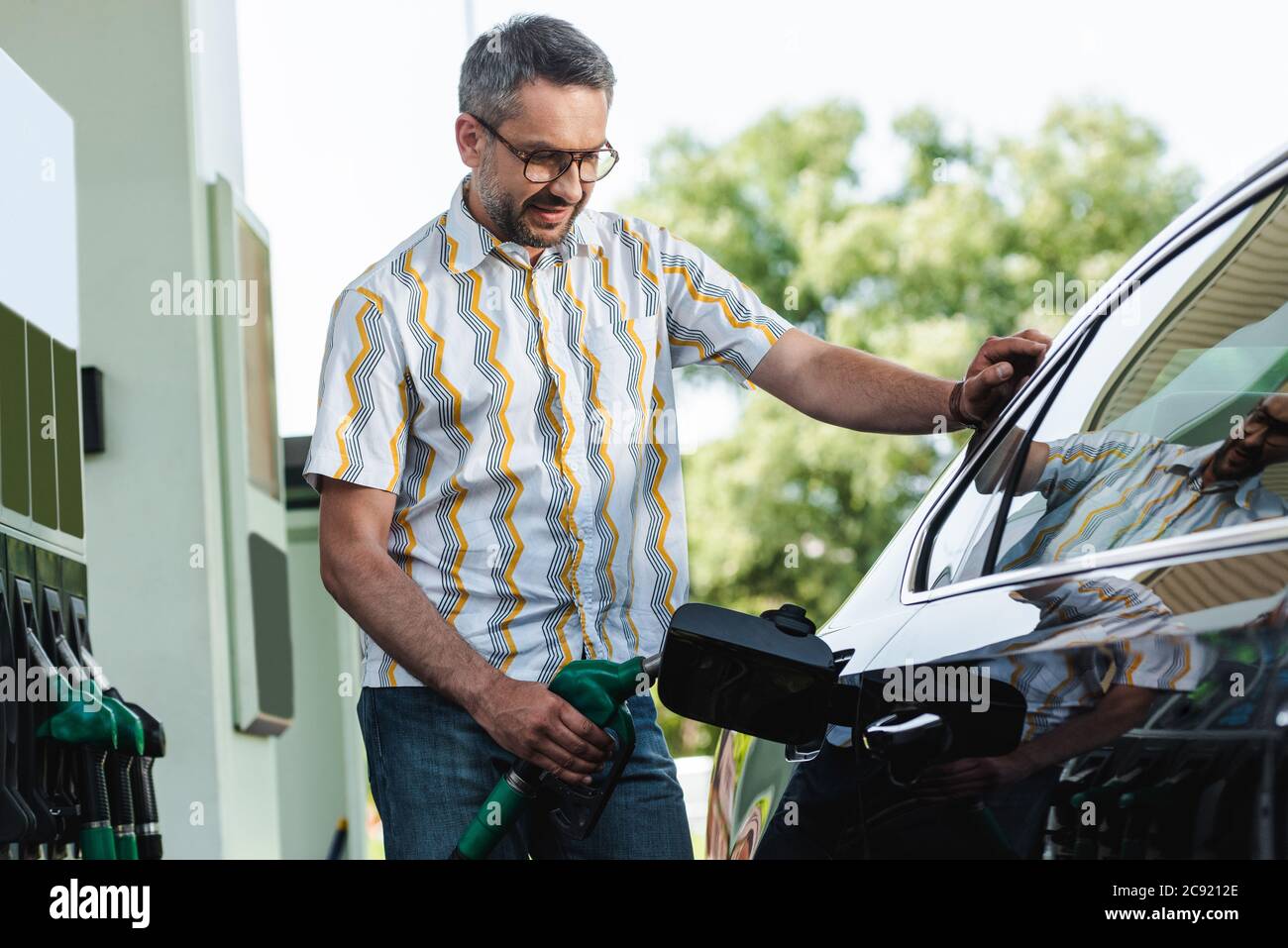 Handsome man refueling car on gas station on urban street Stock Photo ...