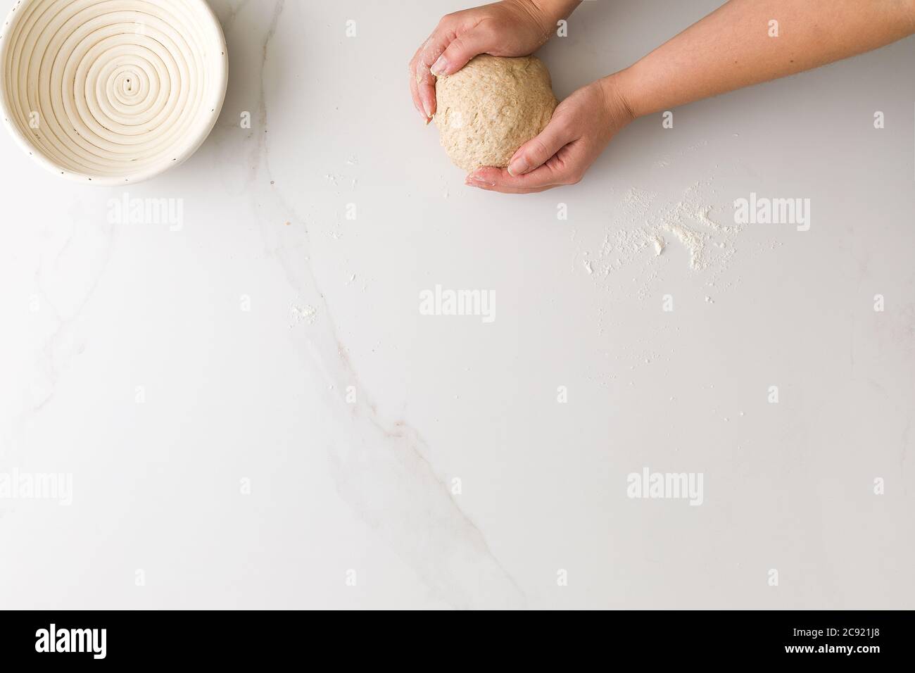 Top view of female hand molding bread dough in a marble table with an ...