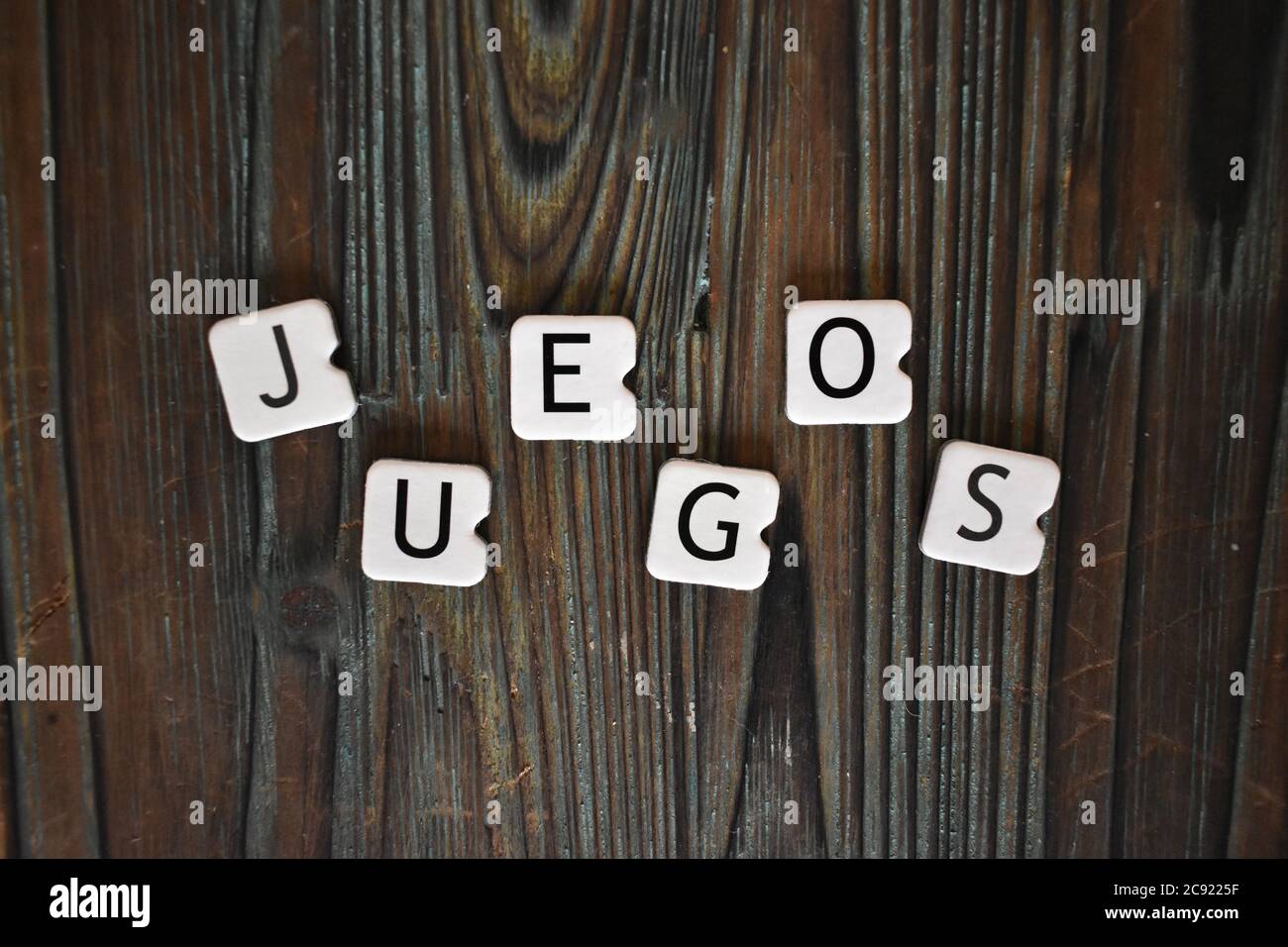 Closeup shot of letters cubes forming the word Juegos on a wooden ...