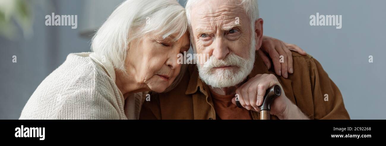 horizontal image of senior woman with closed eyes hugging husband, sick ...