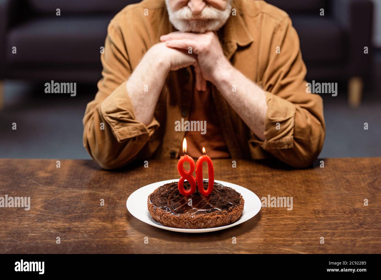 cropped view of lonely senior man leaning on clenched hands and looking ...