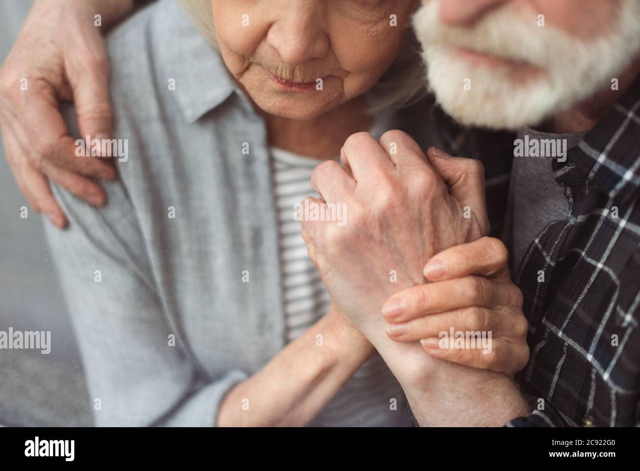 partial view of senior man and his wife, sick on dementia, holding ...