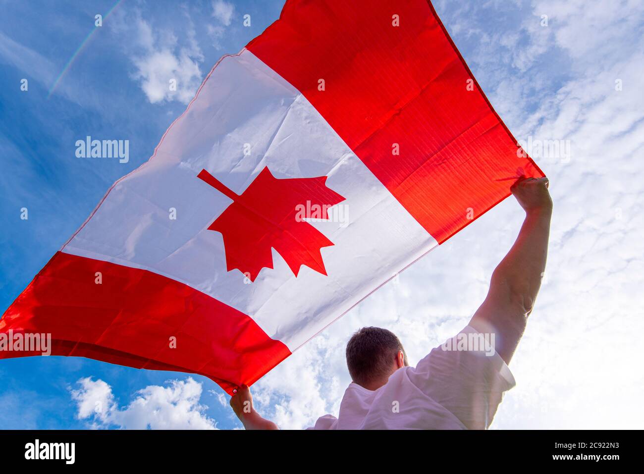 Man holding The National Flag of Canada against blue sky Stock Photo ...
