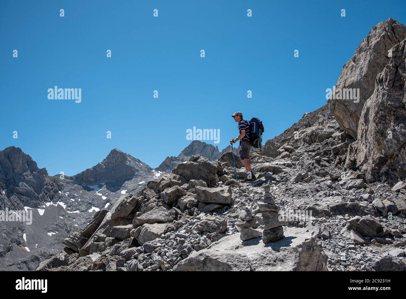 A man stood high in the mountains with his walking pole Stock Photo - Alamy
