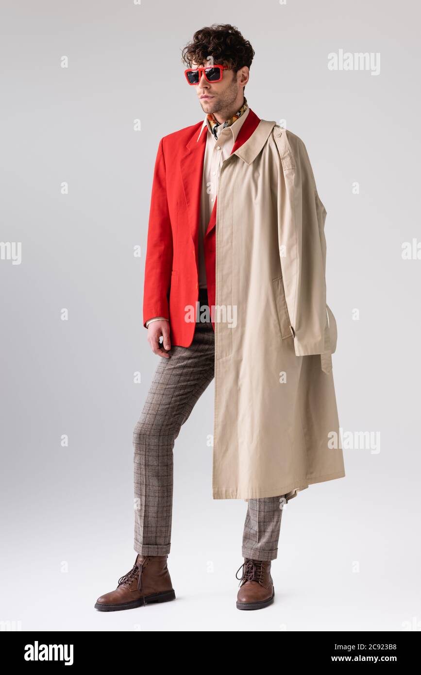 full length view of trendy, confident man with trench coat over ...