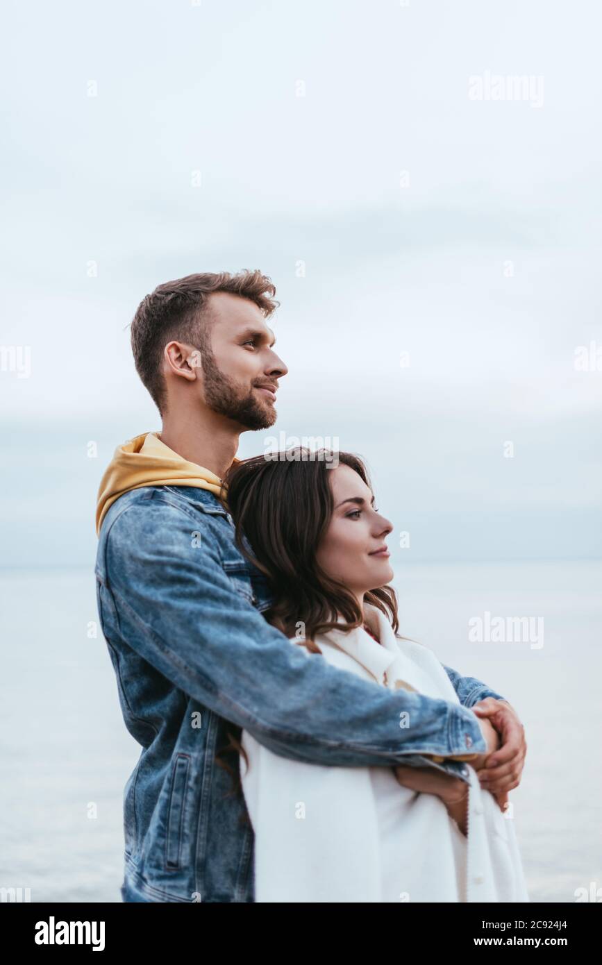 side view of happy man hugging cheerful woman near river Stock Photo ...