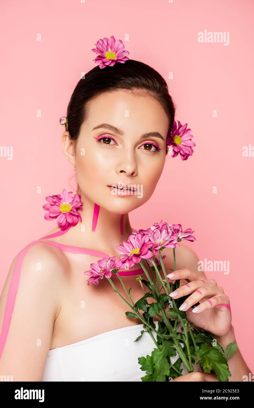 beautiful woman with pink lines on body and flowers in hair holding ...