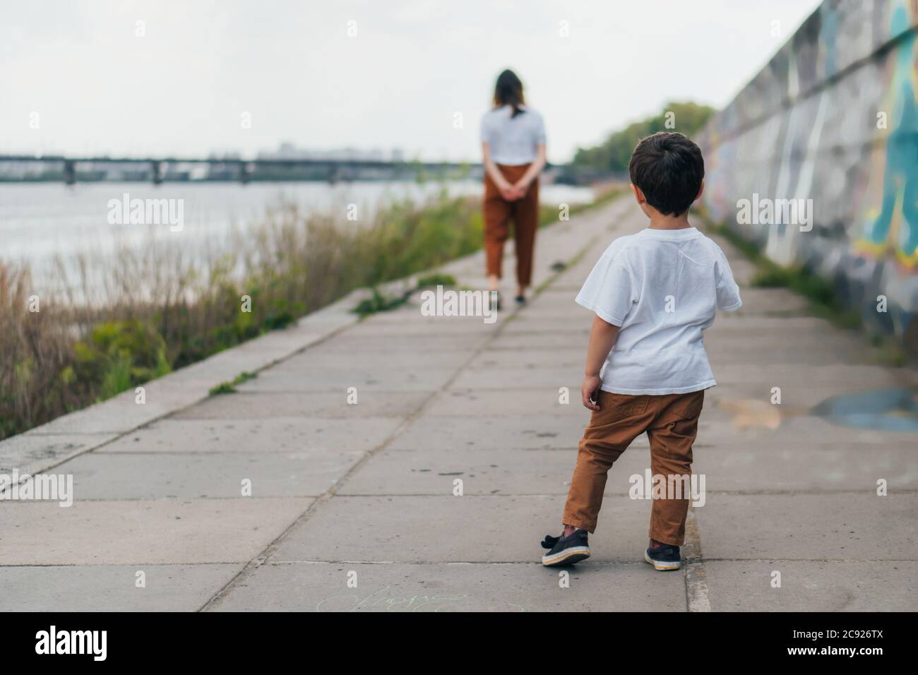 back view of kid standing and looking at mother Stock Photo - Alamy