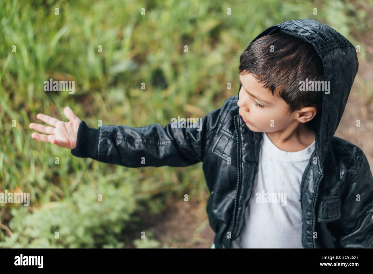 high angle view of cute boy in black jacket standing with outstretched ...