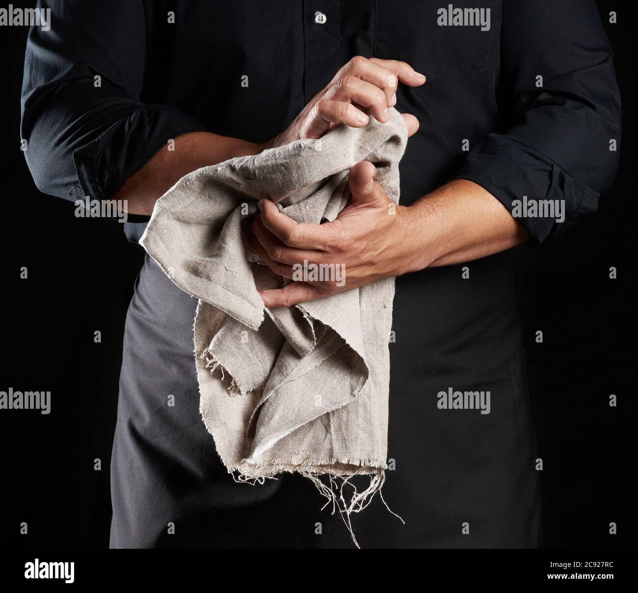 man in black uniform holds gray linen rag and wipes his hands, chef ...