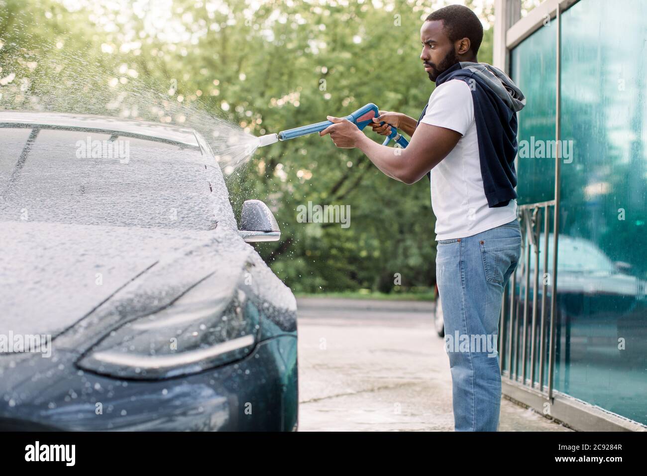 Portrait of handsome bearded young African man washing his modern ...