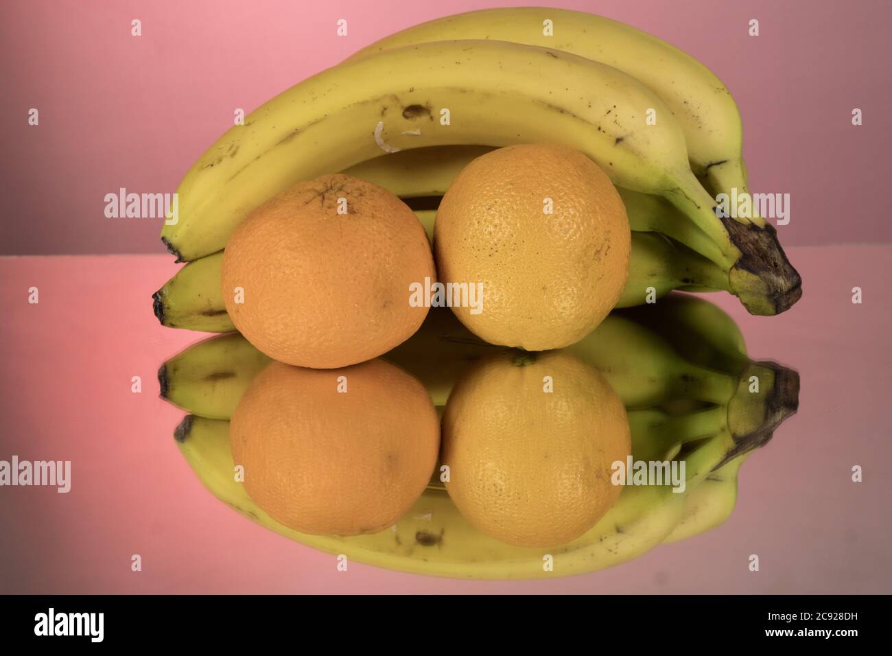 A bunch of bananas and apples on mirroring table on mirror red ...