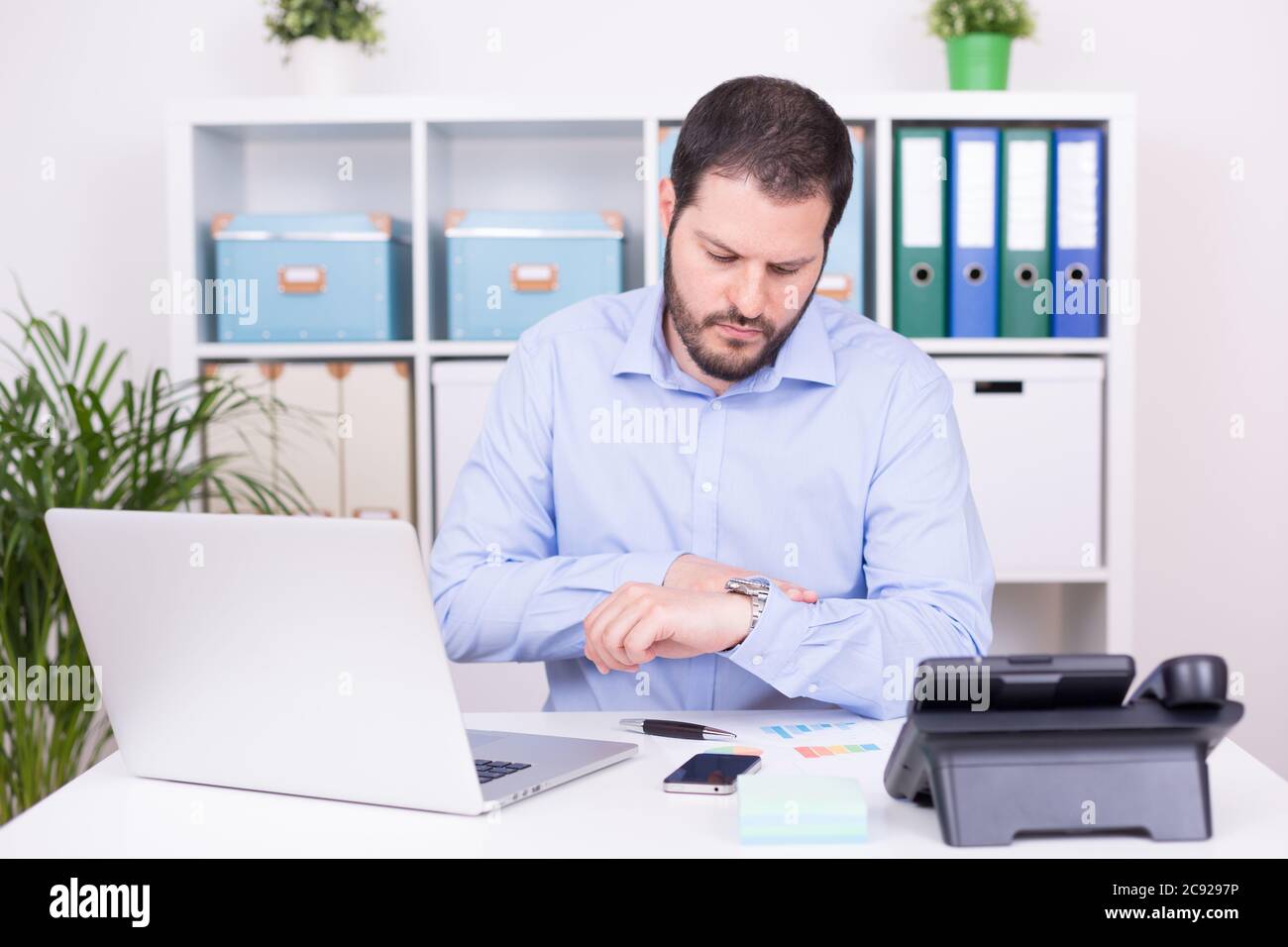 Caucasian man looking at the time in the office Stock Photo - Alamy