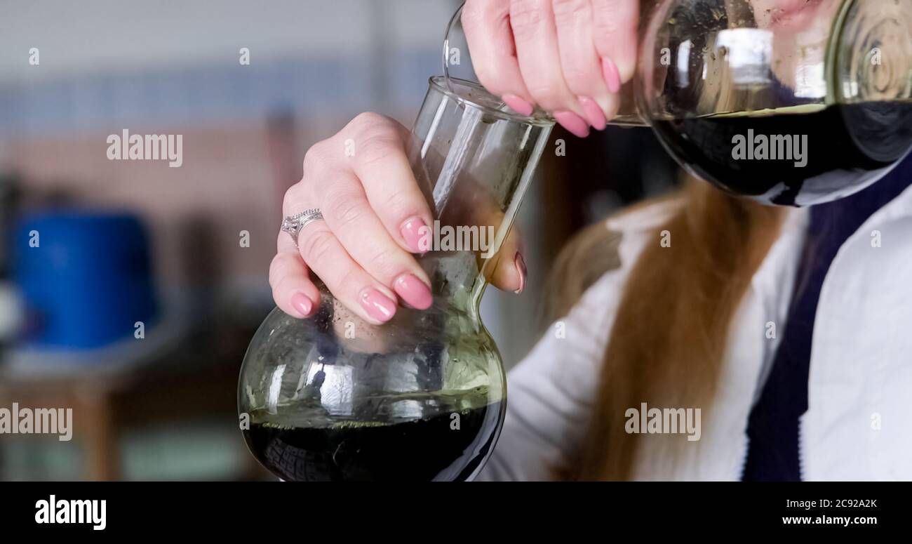 Close up, girl pouring green liquid in the flask making green formula ...