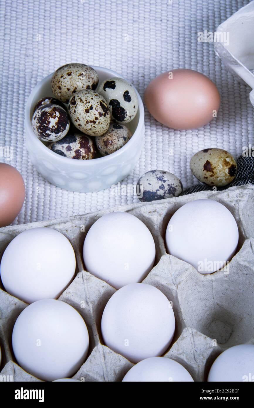 Some healthy native eggs and quail eggs are in a wooden basket next to ...