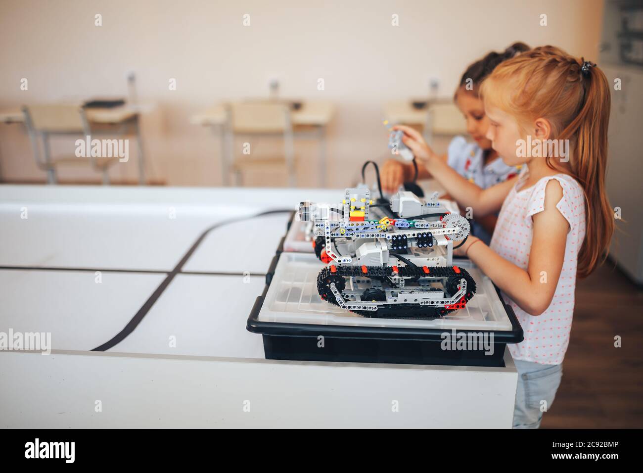 Two schoolgirls study in a robotics class, assemble a robot constructor ...