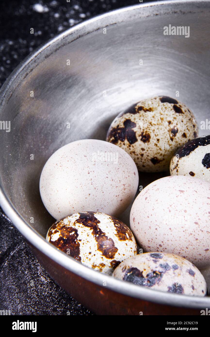 Some healthy native eggs and quail eggs are in a wooden basket next to ...