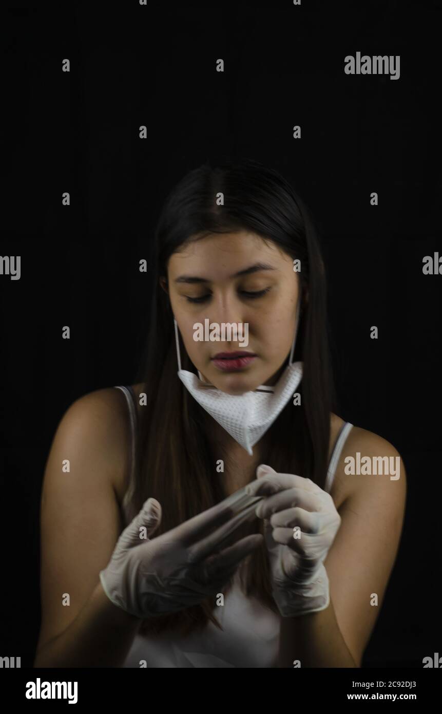 Vertical shot of a tired young female taking off her rubber gloves and ...