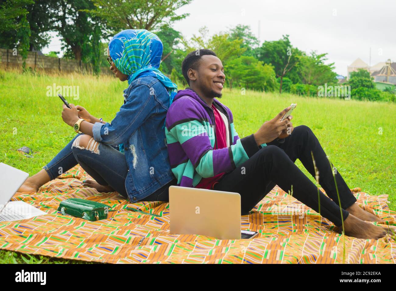 Happy Nigerian couple using their cellphones and laptops while on a ...